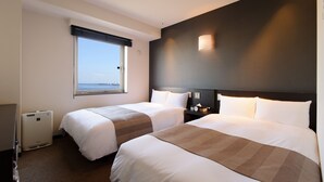 Quarto de hotel com duas camas, uma janela com vista, aquecedor e mesa de cabeceira com luminária.