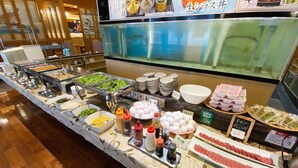 Buffet com diversas opções de comida, incluindo saladas, carnes e acompanhamentos.