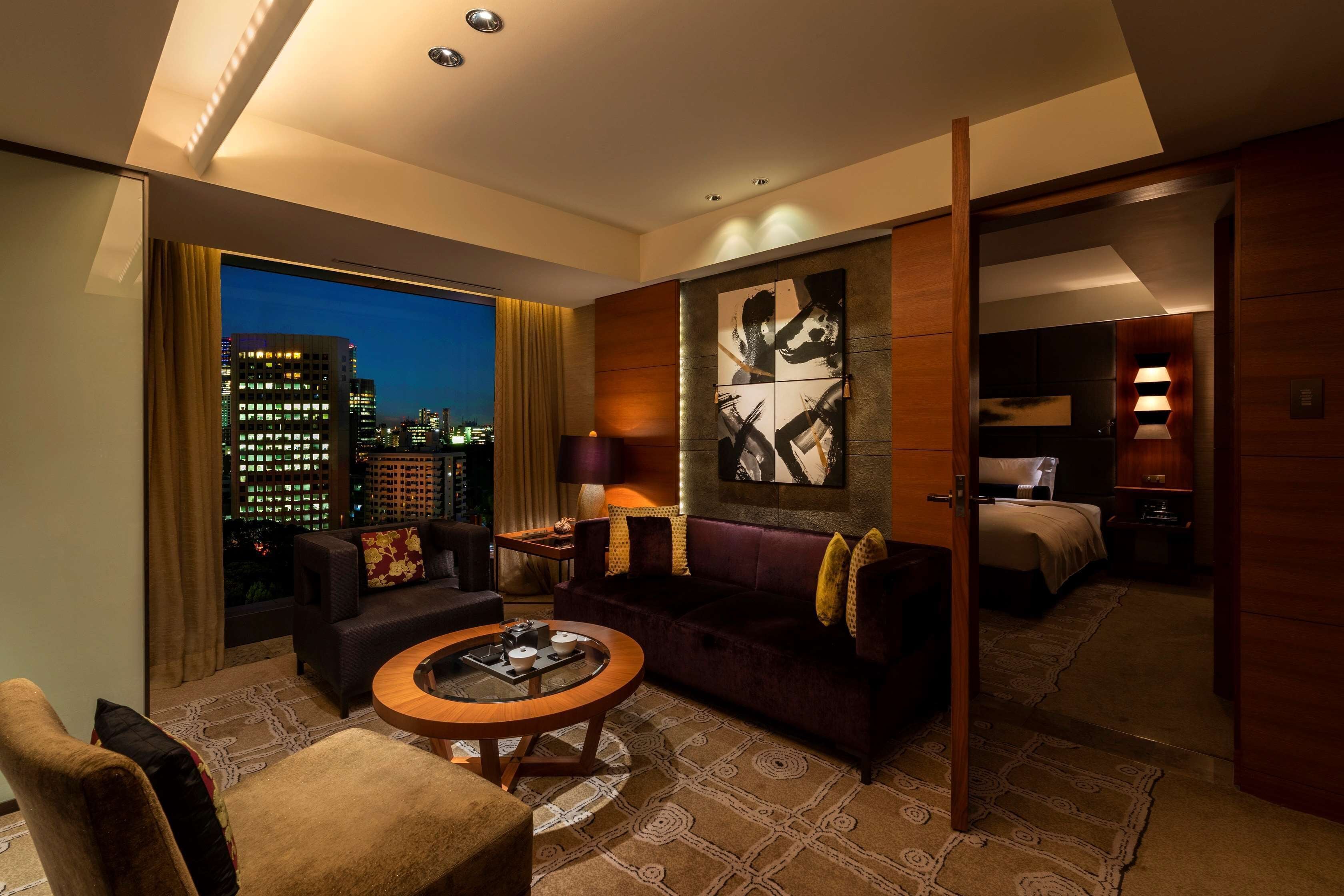Quarto de hotel com vista para a cidade, uma grande pintura abstrata, um sofá, uma mesa de centro e uma cama.