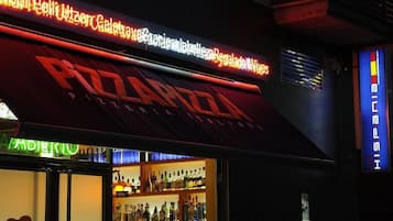 Um restaurante com um letreiro de neon que diz 'PIZZA' e um espaço de bar com prateleiras de garrafas.