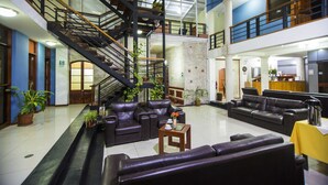Um hall amplo com escada, sofás de couro e plantas em vasos.