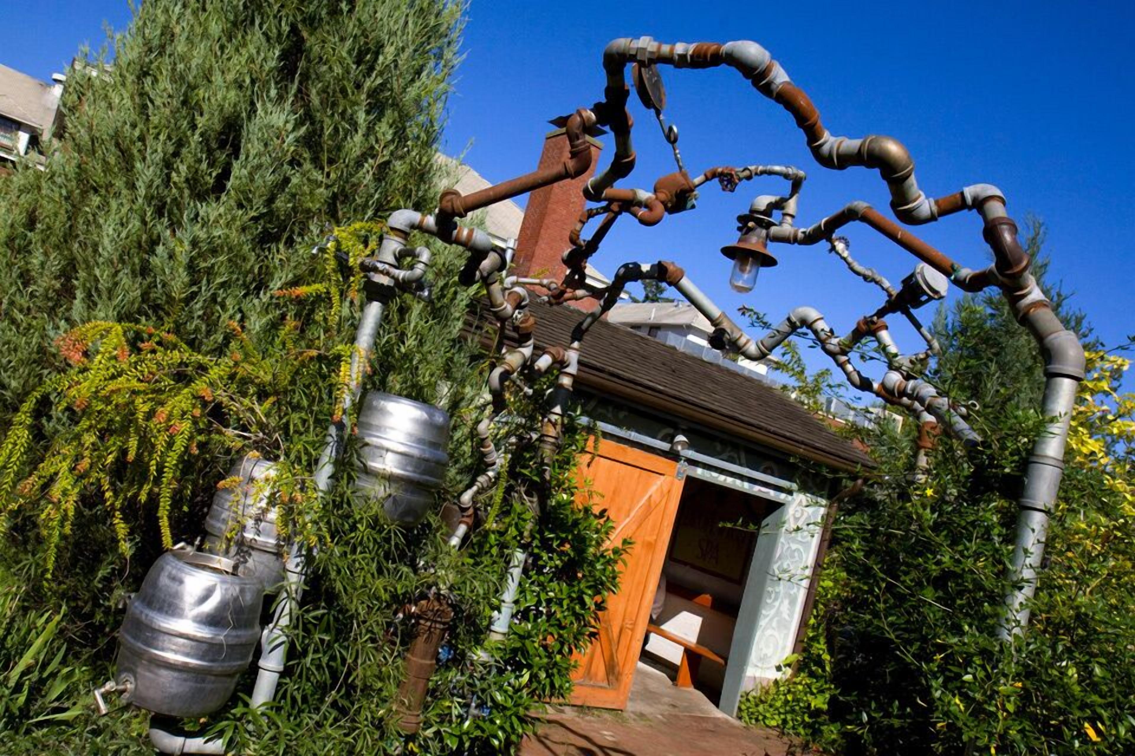 Um jardim com esculturas de metal e uma estrutura de madeira.