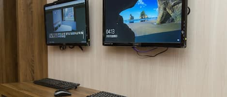 Dois monitores sobre uma mesa com teclados e mouses.