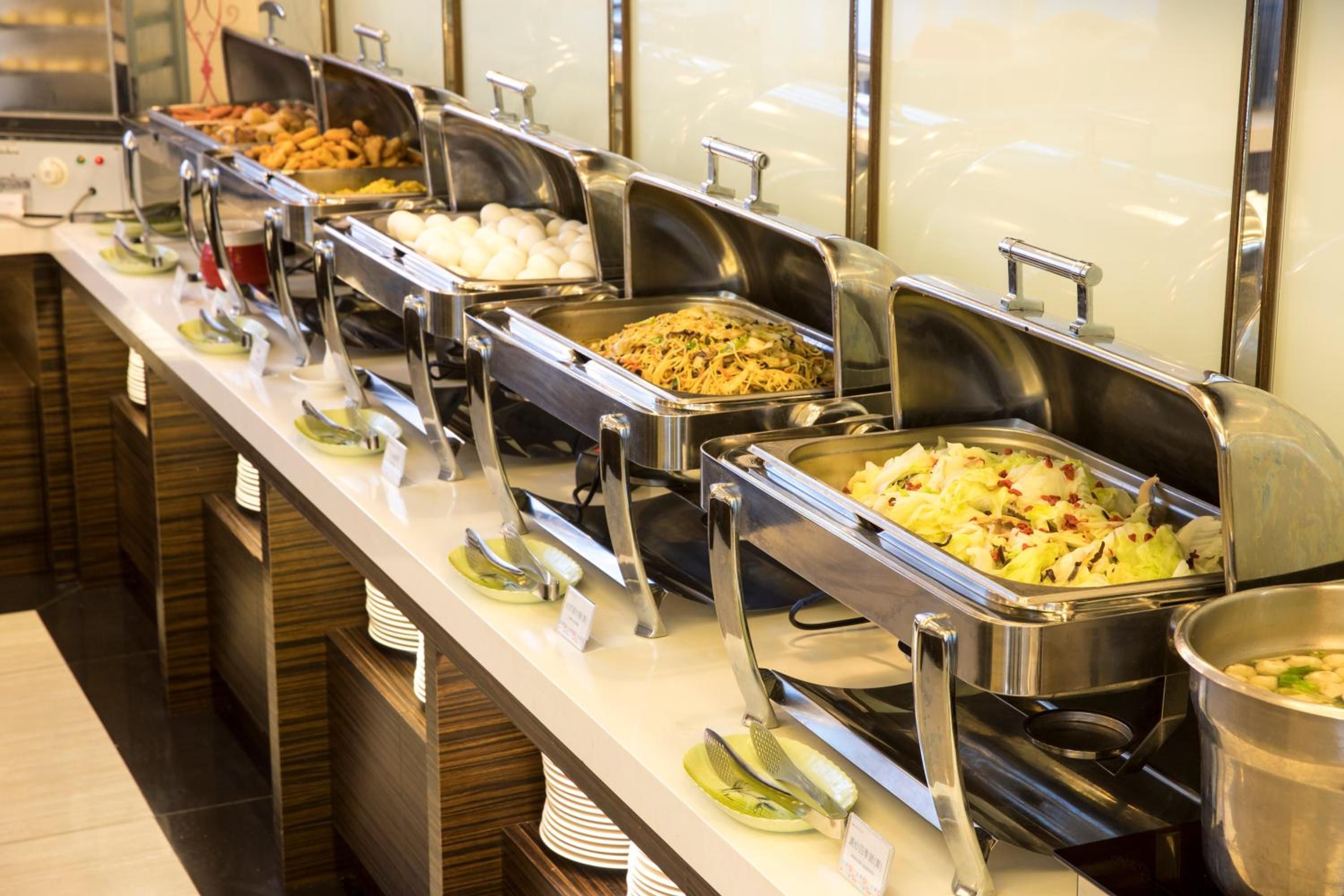 Buffet com diversas opções de comida, incluindo ovos, saladas e outros pratos.