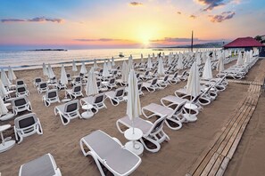 Uma praia privada, espreguiçadeiras, guarda-sóis de praia 
