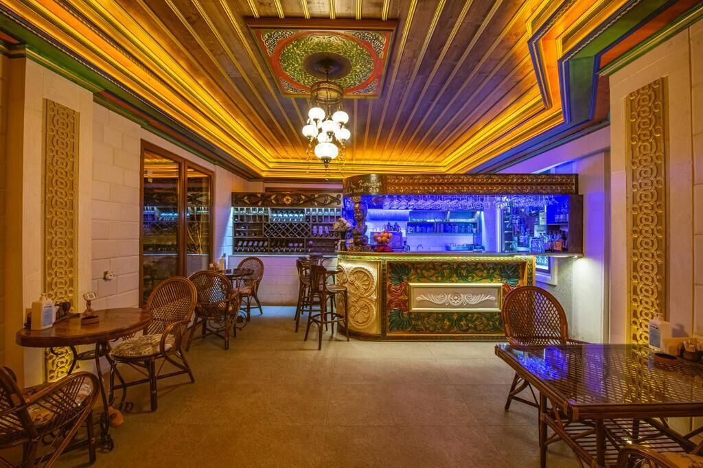 Uma área de bar com teto decorativo, balcão e cadeiras de vime.