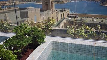 Piscina no terraço com vista desobstruída para um edifício histórico e um porto.