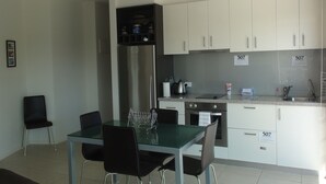 Uma cozinha compacta com geladeira, forno e um espaço de jantar com cadeiras e mesa.