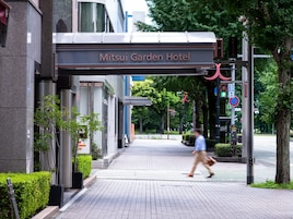 Entrada do Mitsui Garden Hotel, com galeria coberta e faixa de pedestres.