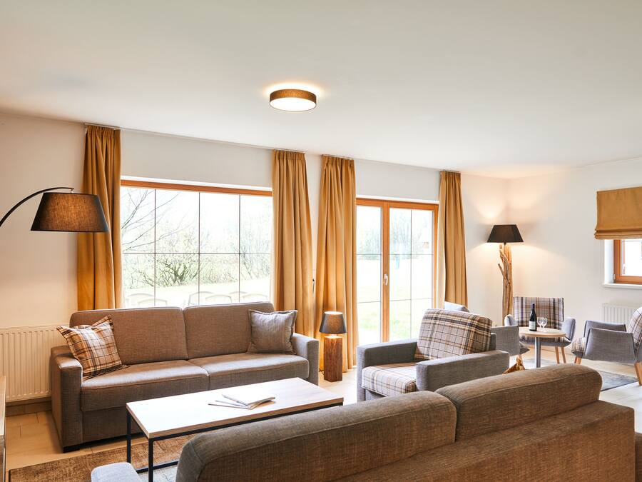 Uma sala de estar moderna com sofá, poltronas, mesa de centro e abajur.