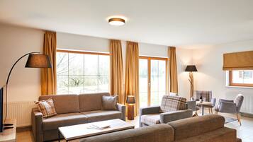 Uma sala de estar moderna com sofá, poltronas, mesa de centro e espaço para refeições.