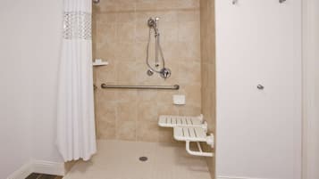 Uma área de chuveiro com barra de apoio, chuveiro manual e assento de banho branco.
