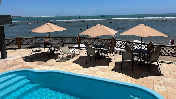 Uma área à beira da piscina com mobiliário de exterior e vista para o mar.