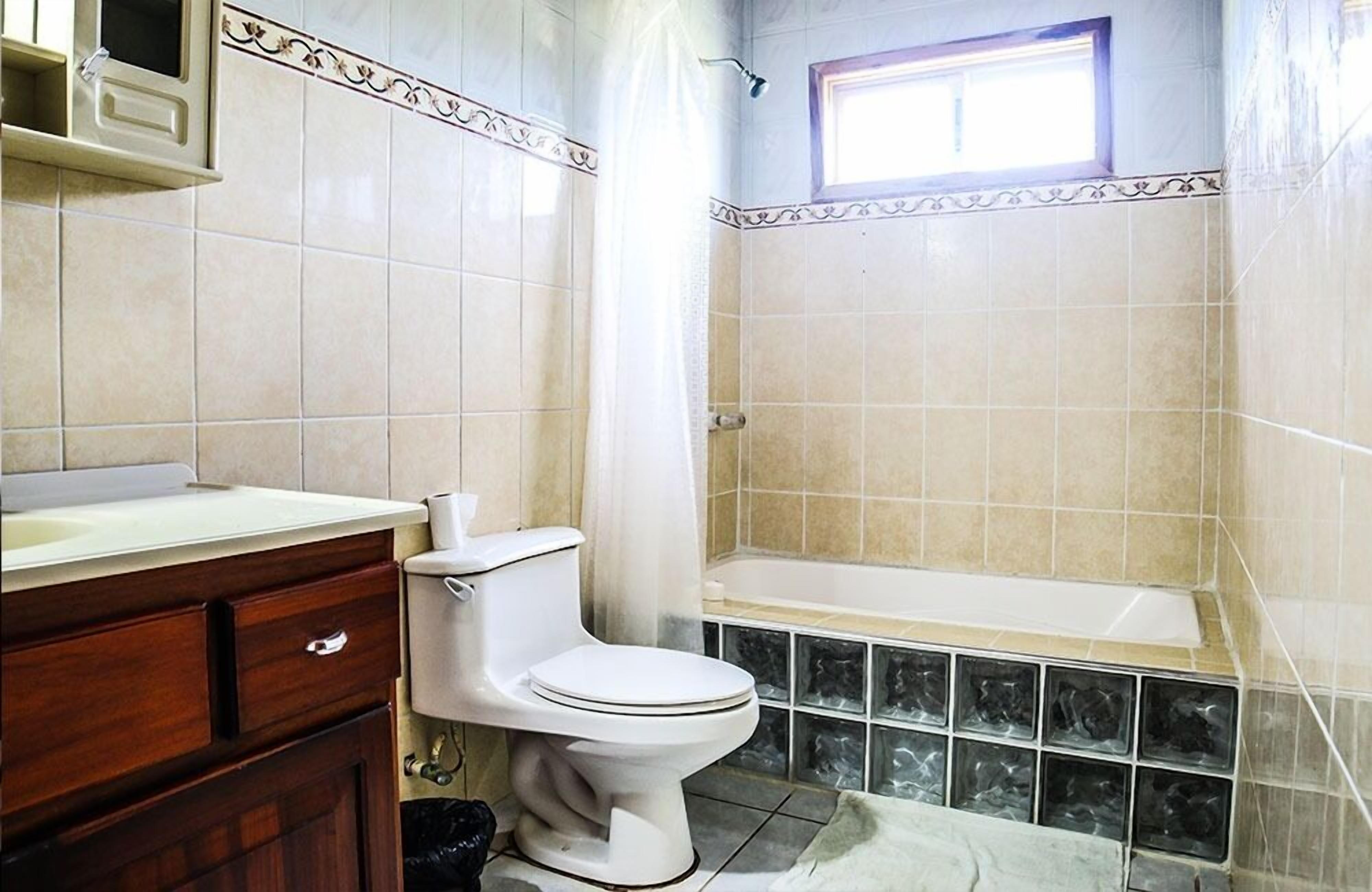 Uma casa de banho com sanita, lavatório, espelho e banheira.
