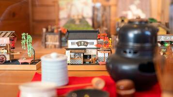 Uma miniatura de uma aldeia tradicional japonesa, com casas de madeira, um bule de chá e uma pequena loja.