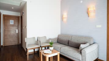 Uma sala de estar moderna com um sofá cinzento, duas poltronas, uma mesa de centro de madeira e uma pequena planta em vaso.