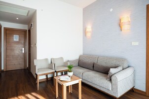 Uma sala de estar moderna com um sofá cinzento, duas poltronas, uma mesa de centro de madeira e uma pequena planta em vaso.