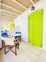Um quarto com teto branco, porta verde e uma mesa com cadeiras.