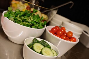 Três tigelas brancas com legumes frescos, incluindo alface, tomates cereja e fatias de pepino.