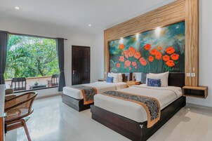 Quarto de hotel com duas camas, uma janela grande com cortinas, um quadro de flores na parede e uma varanda com vista para o verde.
