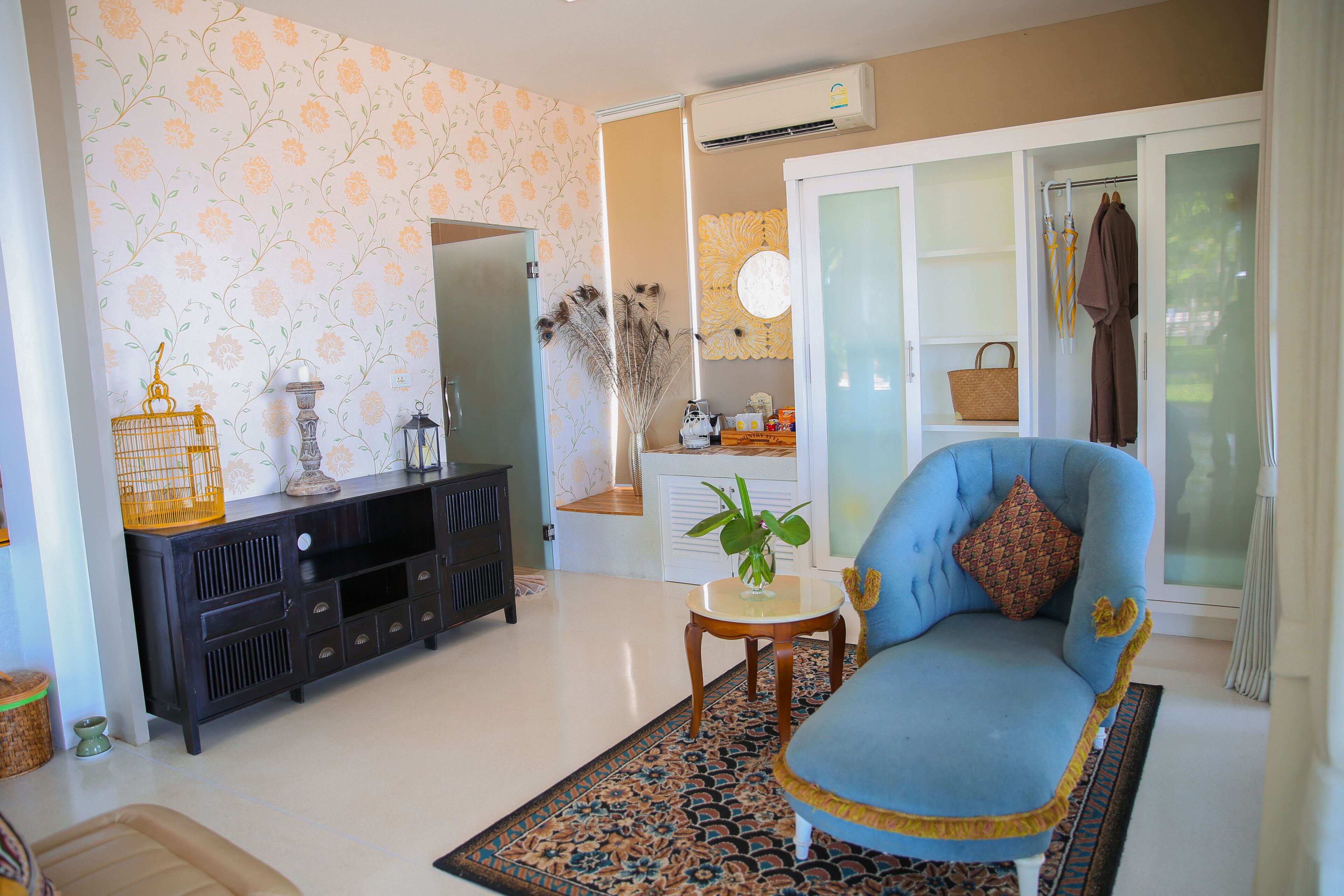 Sala de estar com um sofá azul, um rack preto, um tapete estampado e um espelho decorativo.