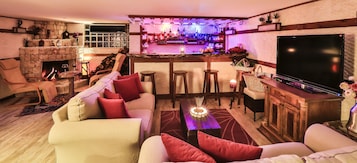Uma sala de estar aconchegante com lareira, espaço de bar e uma grande televisão de tela plana.
