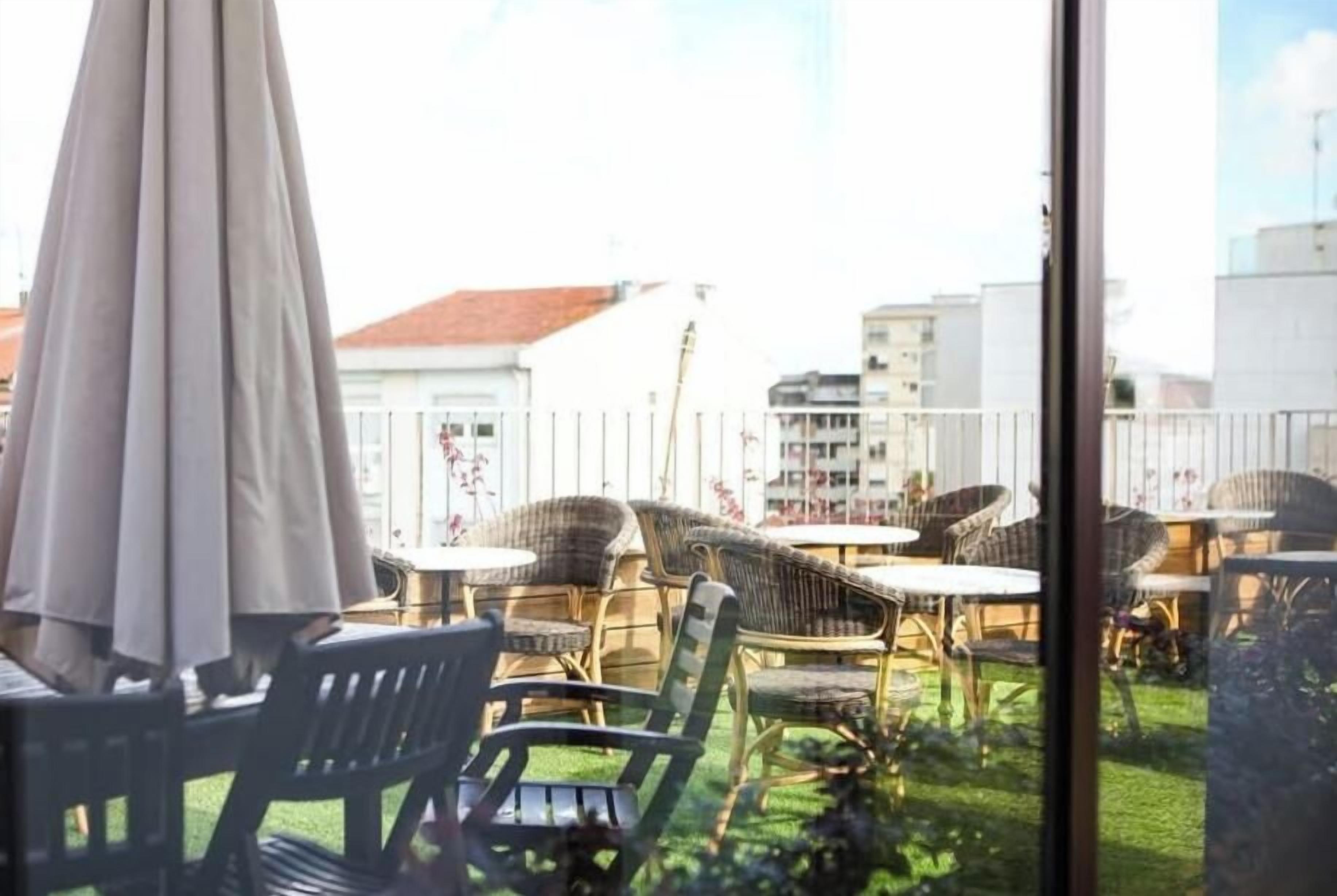 Uma área de estar ao ar livre com móveis de vime e um guarda-sol branco.