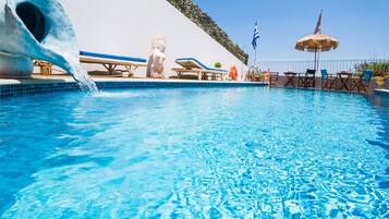 Piscina com escorregador, espreguiçadeiras e bandeiras.