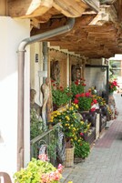 Varanda de madeira com floreiras, uma cesta de vime e um banco.