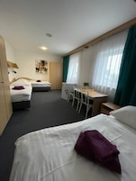 Quarto de hotel com duas camas, uma escrivaninha e uma cadeira.