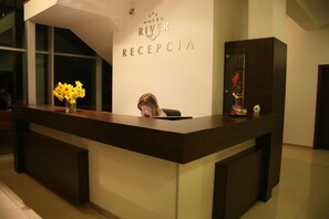 Balcão de recepção de hotel com uma placa que diz 'HOTEL RIVER RECEPCIA'.