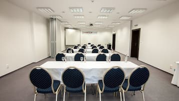 Uma sala de conferências com uma mesa comprida, cadeiras e uma tela de projetor.