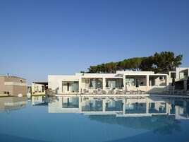 Um hotel moderno com piscina, área de estar ao ar livre e uma grande árvore.