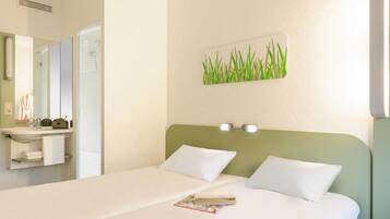Quarto de hotel com cama, mesa de cabeceira, espelho, um quadro na parede com grama e janela com persianas.