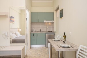 Uma cozinha compacta com armários verde-água, lava-louças e um espaço de jantar com mesa e cadeiras.