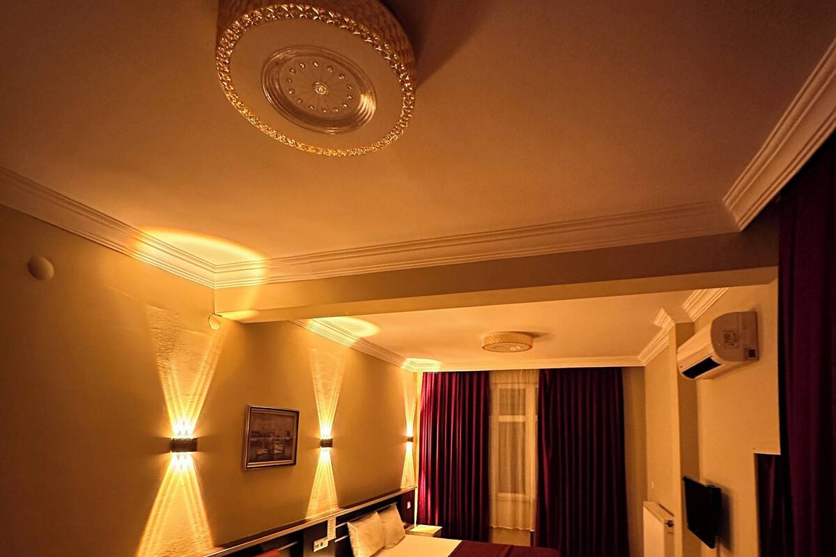 Quarto de hotel com cama, escrivaninha, cadeira e televisão.