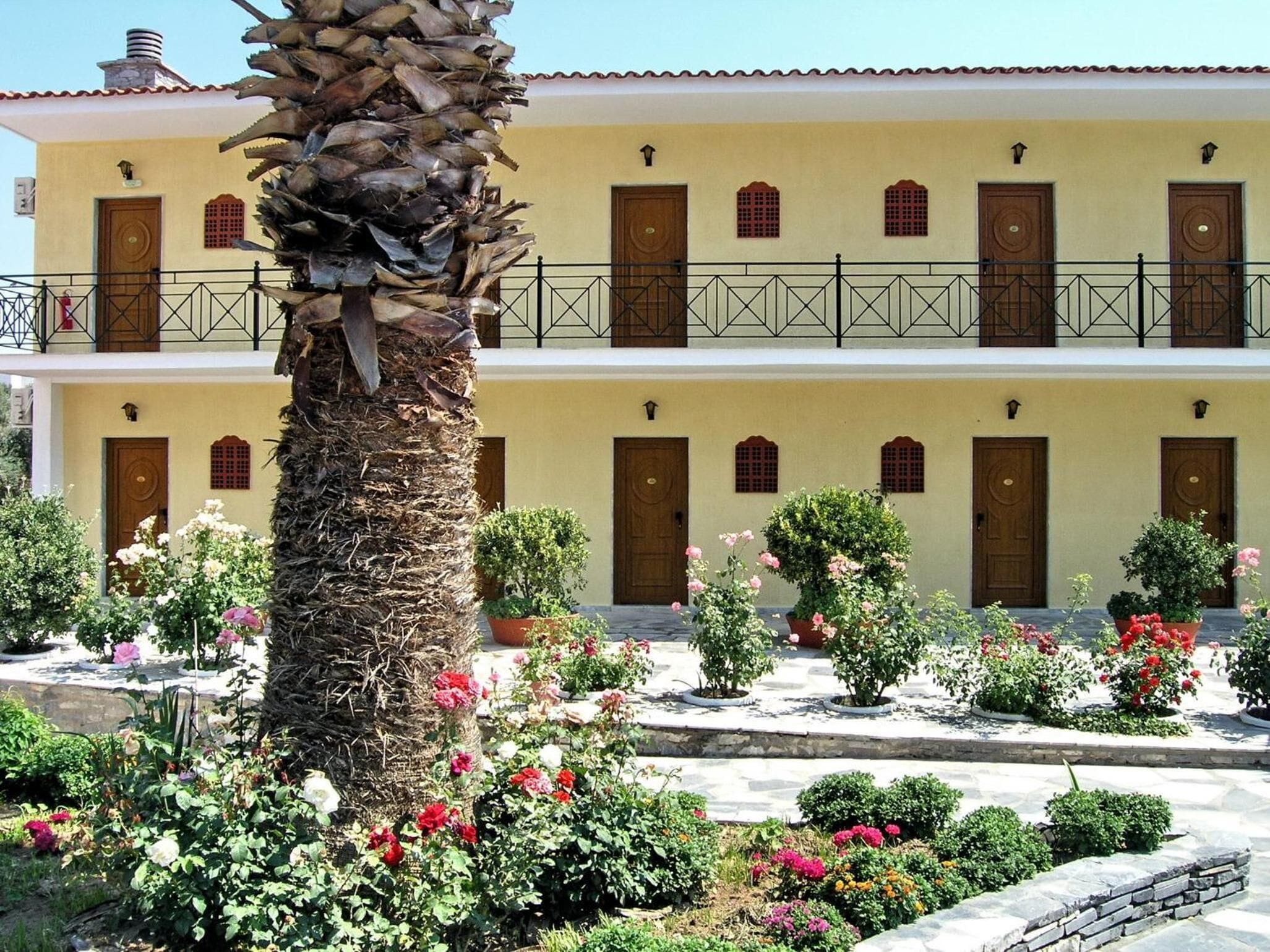 Um edifício de dois andares com fachada amarela, várias portas e uma varanda com grade.