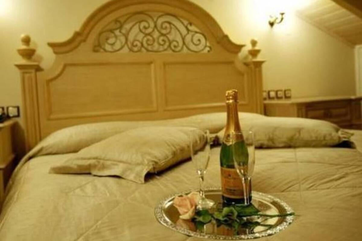 Uma cama com uma garrafa de champanhe, copos e um tabuleiro.