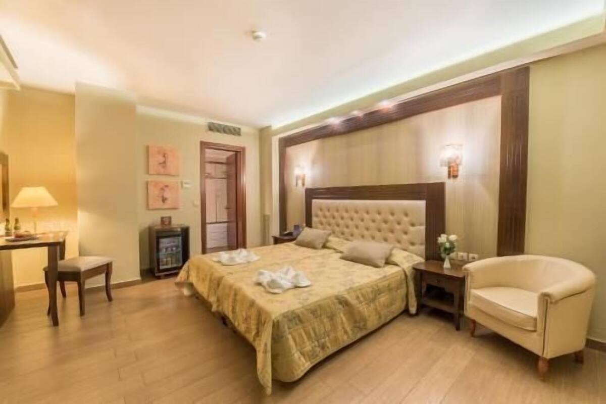 Quarto de hotel com cama, mesa de cabeceira, cadeira, luminária e obra de arte na parede.