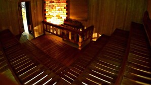 Um quarto com piso de madeira, parede de tijolos e um banco de madeira.