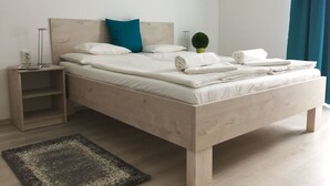 Quarto moderno com cama, mesa de cabeceira e uma pequena planta verde.