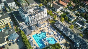 Vista aérea de um hotel com uma piscina grande, vários edifícios e vegetação ao redor.