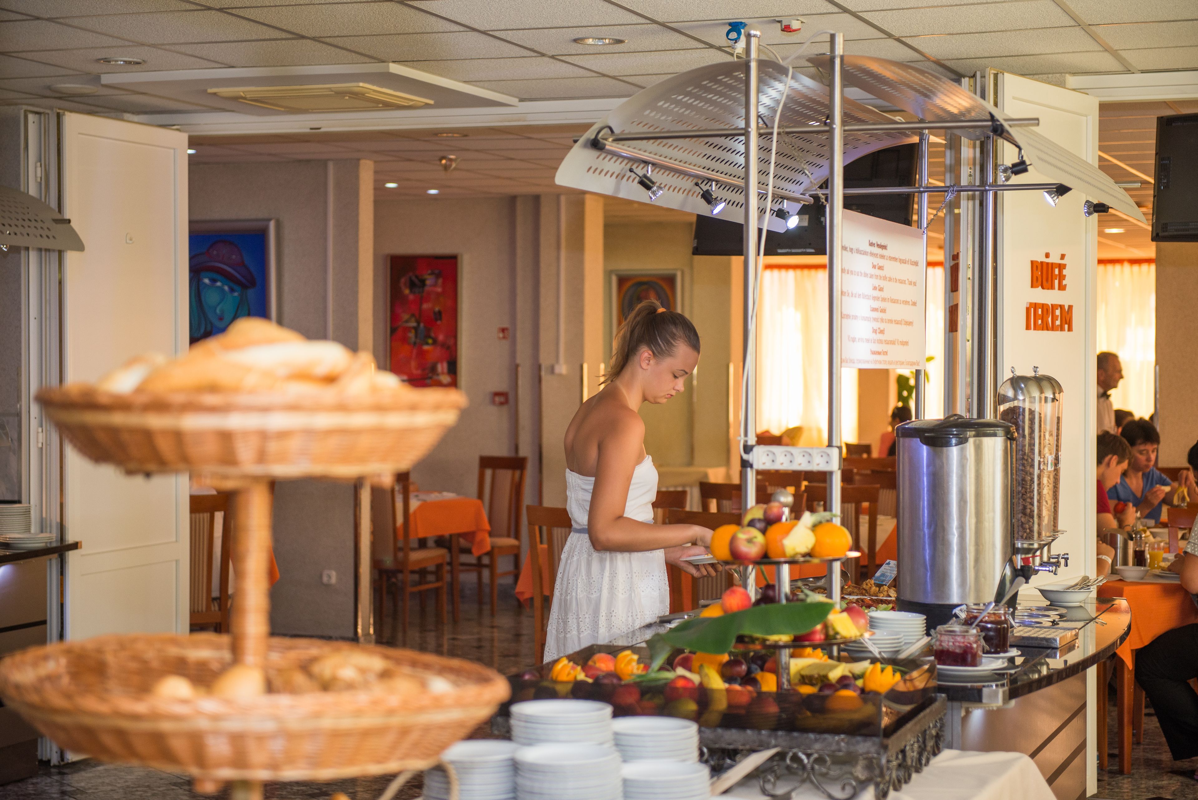 Disposição de buffet com diversas frutas e um dispensador de bebidas.