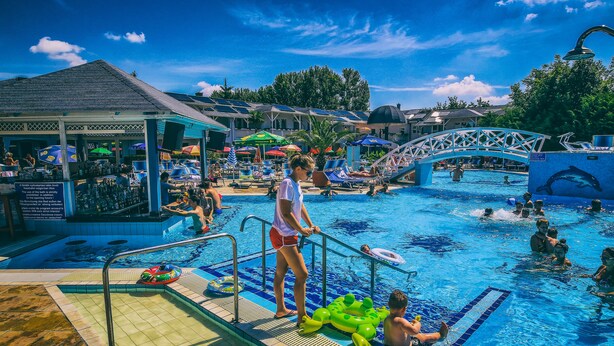 Uma área de piscina com posto de salva-vidas, espreguiçadeiras e parque infantil.