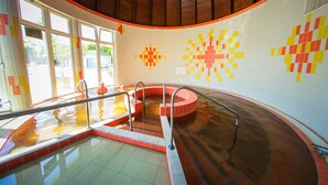 Uma piscina com design curvo, paredes revestidas com padrões geométricos e teto de madeira.