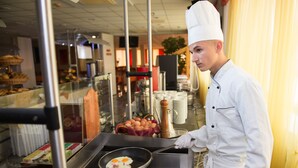 Um cozinheiro com uniforme branco cozinhando em um fogão.