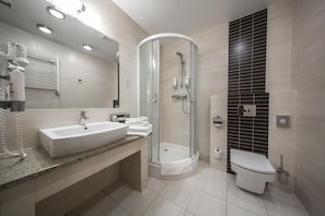 Um banheiro moderno com chuveiro de vidro, pia com bancada de mármore e vaso sanitário.