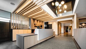 Uma área de recepção moderna com balcão, ripas de madeira e iluminação pendente.