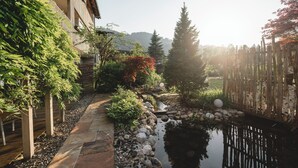 Um jardim tranquilo com um caminho de pedra, um pequeno lago e uma cerca de madeira.
