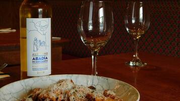 Uma garrafa de vinho, duas taças de vinho vazias e uma tigela de massa sobre uma mesa.